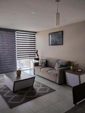 Uma sala de estar moderna com sofá, mesa de centro e mesa lateral.