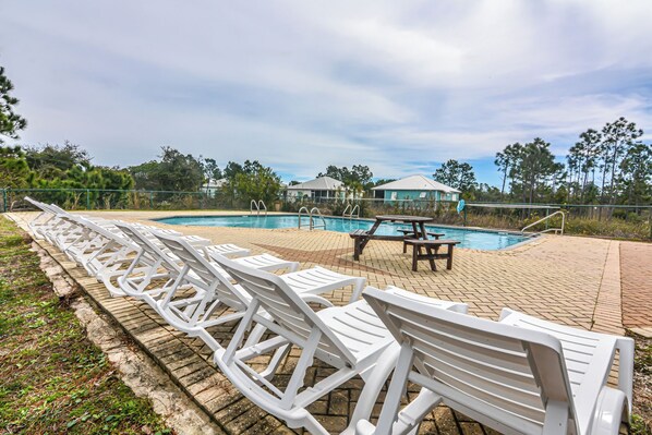 Área de piscina com espreguiçadeiras e mesa para piquenique.