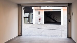 Um espaço interno com piso de azulejos, teto com iluminação embutida e uma porta que dá para área externa com escadaria.