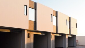 Um edifício moderno com várias garagens, piso pavimentado e céu claro.
