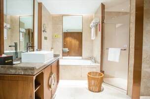 Uma casa de banho moderna com um espelho grande, toucador com lavatório, zona de duche e sanita.