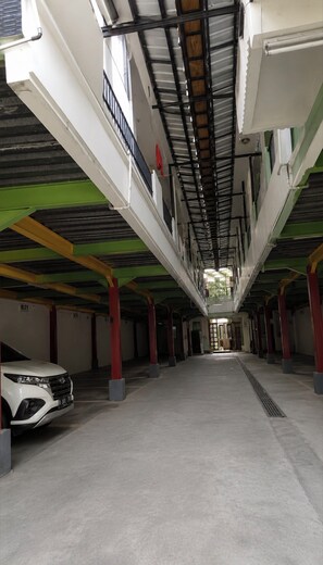 Garagem subterrânea com vários níveis, pisos de concreto e vigas de metal.