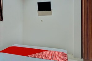 Um quarto com uma cama, uma pequena janela e uma porta.