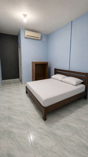 Quarto com cama, ar condicionado, mesa de cabeceira e porta.