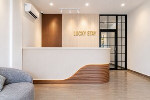 Uma receção de design moderno, um letreiro com a inscrição 'LUCKY STAY' e uma porta com painel de vidro.