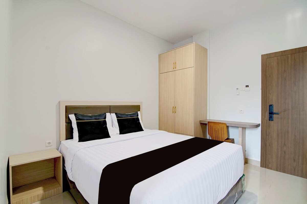 Quarto de hotel com uma cama, um guarda-roupa, uma mesa de cabeceira e uma porta.
