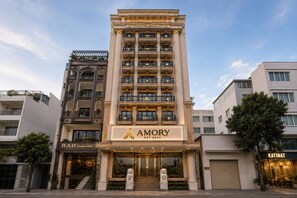 Um hotel de vários andares com uma entrada imponente, uma estátua na base e varandas com grades ornamentadas.