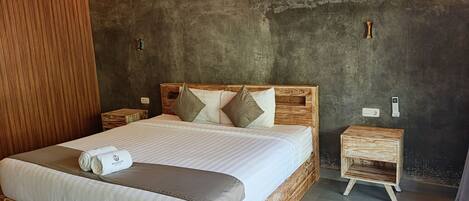 Quarto moderno com cabeceira de madeira, cama grande com roupa de cama branca e mesa de cabeceira com abajur.