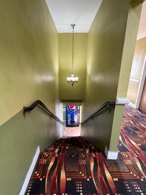 Um corredor com carpete estampado, um banner da Pepsi e um candelabro.