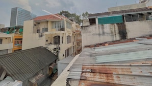 Um edifício de vários andares com telhado de telhas vermelhas, varanda e uma janela grande.