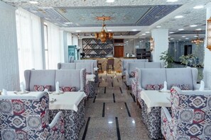 Restaurante com cabines, área de bar e teto estampado.