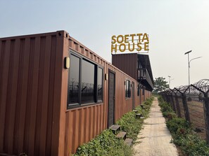 Um edifício moderno com uma placa indicando 'SOETTA HOUSE' e um caminho que o leva até ele.