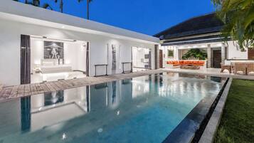 Uma casa moderna com piscina, sala de estar com sofá e espaço para refeições.