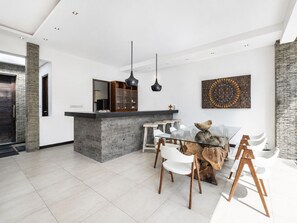 Uma cozinha moderna com uma ilha central, cadeiras brancas e uma mesa de jantar.