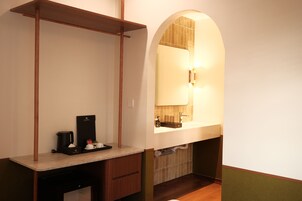 Casa de banho com toucador de madeira, máquina de café e espelho com luz.