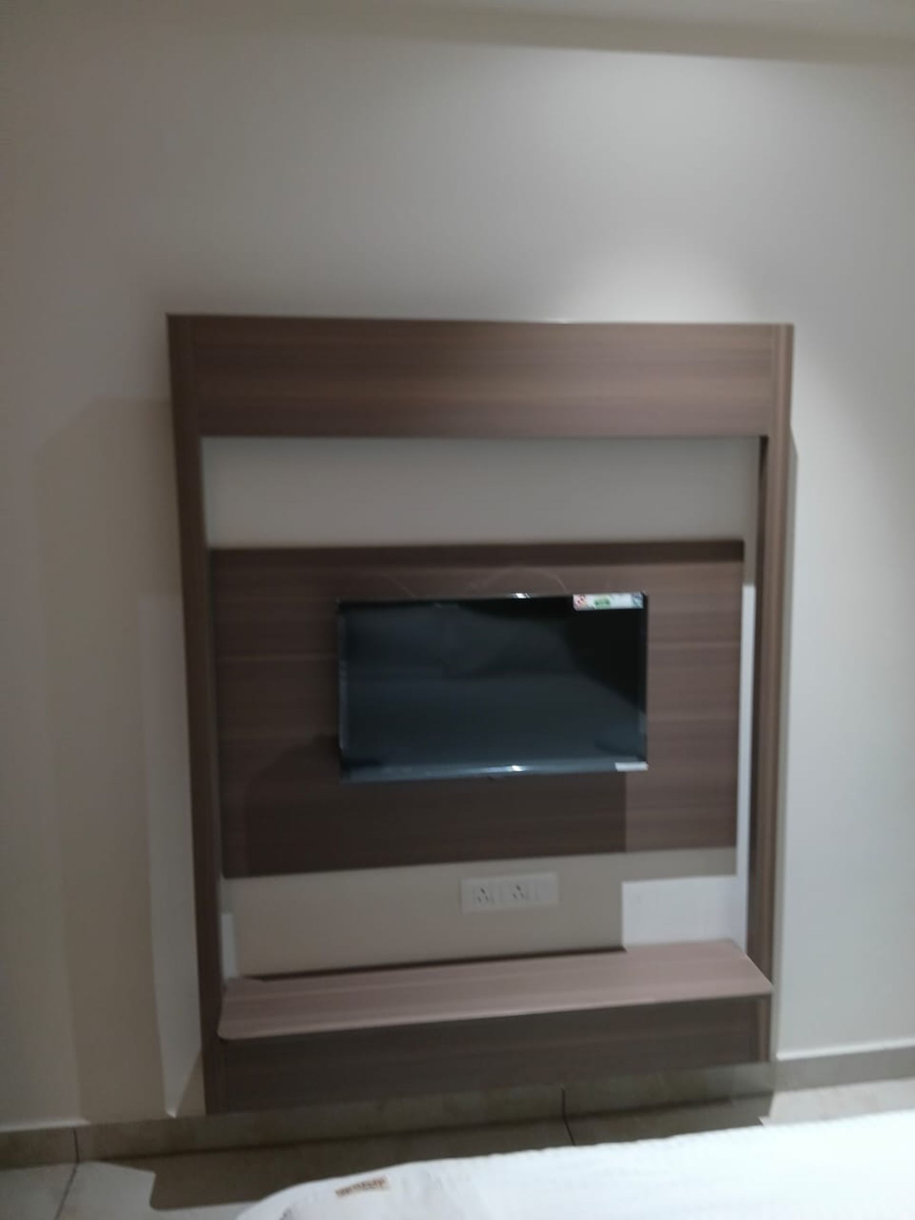 Quarto moderno com TV embutida em parede de painel de madeira.