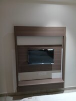 Quarto moderno com TV embutida em parede de painel de madeira.