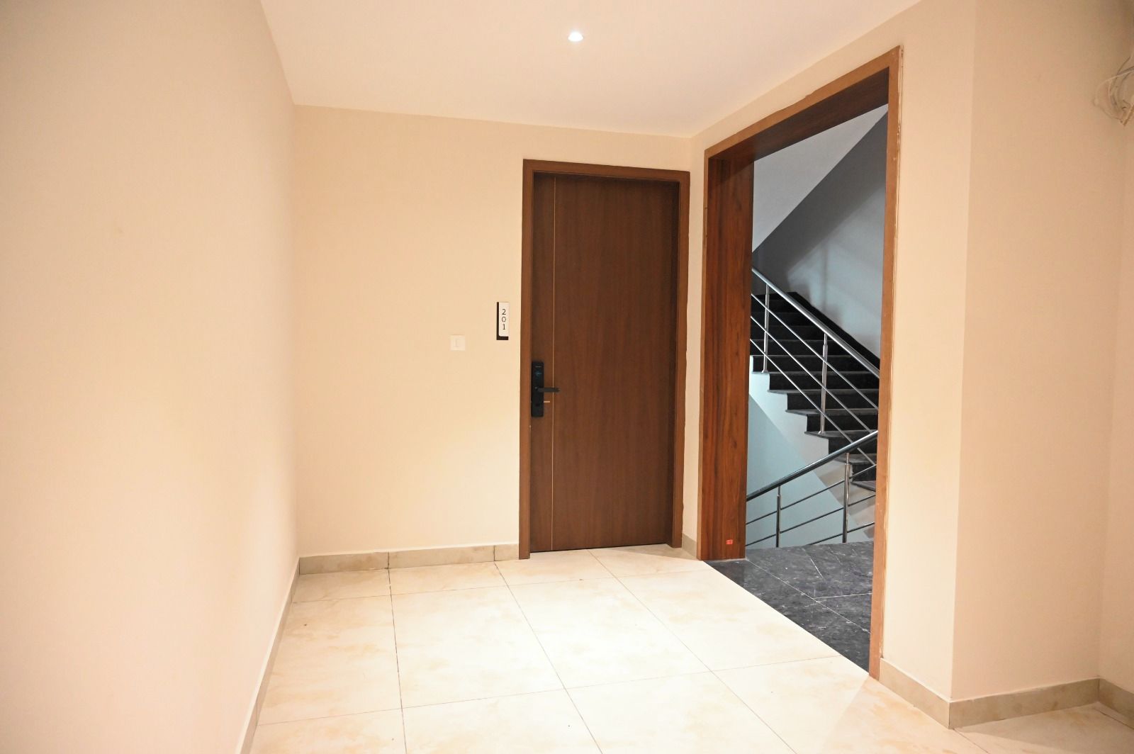 Corredor com porta de madeira e escada que leva a um andar superior.