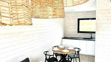 Um interior moderno com sofá, mesa de jantar, cadeiras e luminárias de vime.