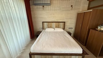 Quarto com cama de madeira, guarda-roupa e ar condicionado fixado na parede.