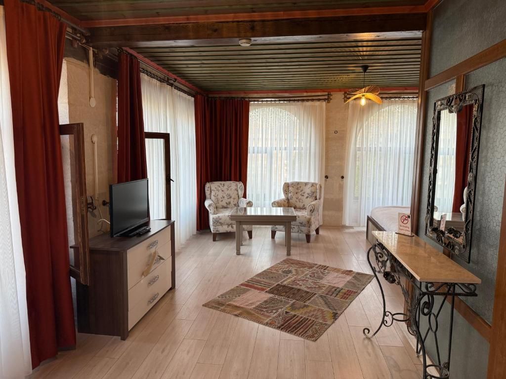 Uma sala de estar com televisão, duas poltronas, uma mesa de centro e um tapete estampado.