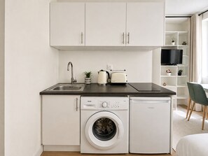Cozinha compacta com máquina de lavar, torradeira e pia.
