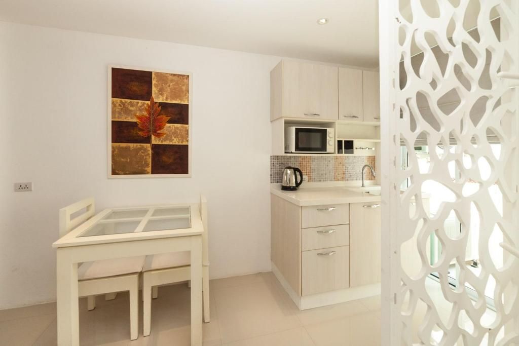 Cozinha moderna com micro-ondas, chaleira e mesa com cadeiras.