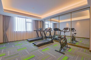 Sala de ginástica de hotel com esteiras, elíptica e bicicleta ergométrica.