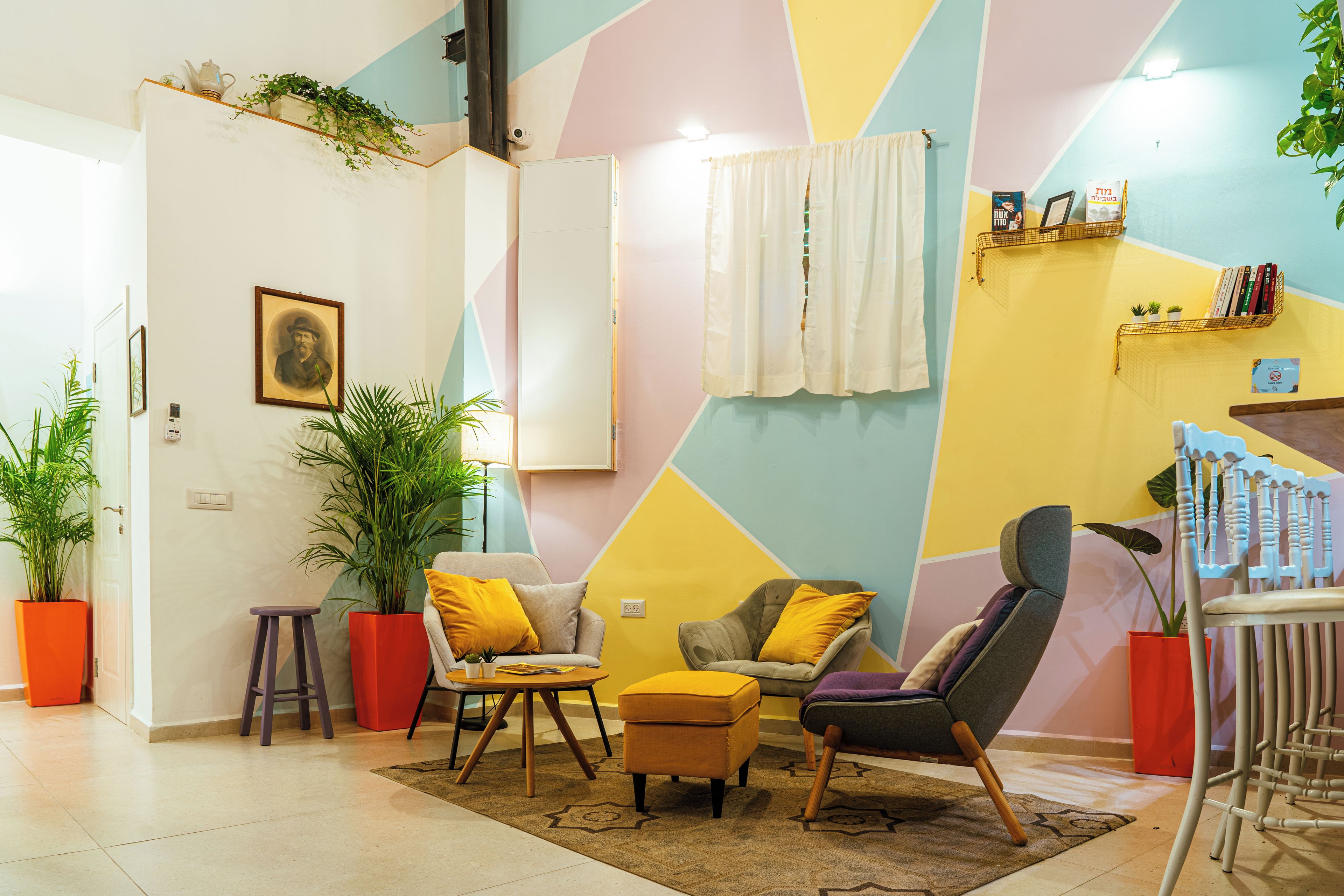 Uma sala de estar com sofá, cadeiras, mesa de centro, tapete e estante de livros.