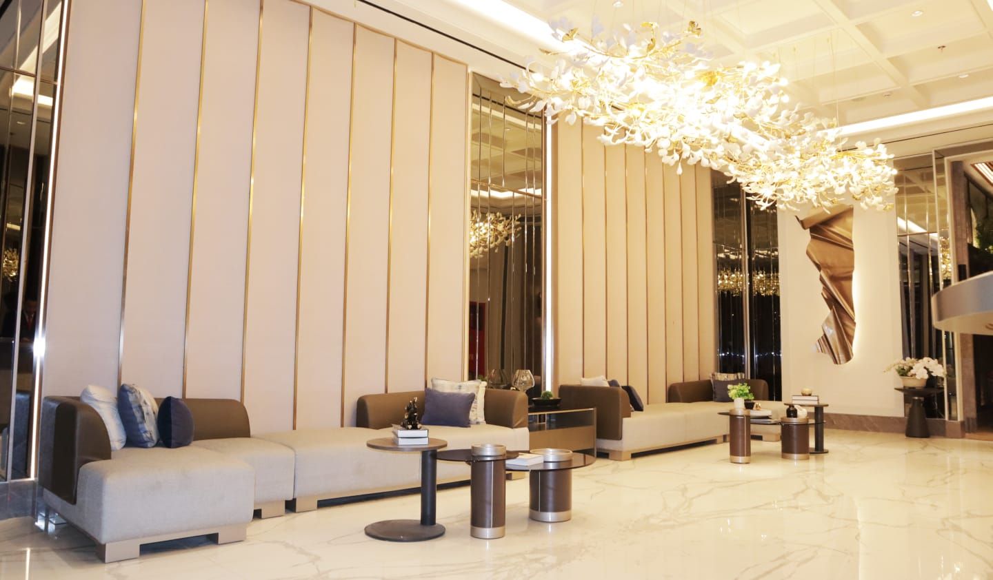 Um lobby moderno com um sofá, duas mesinhas laterais e um lustre decorativo.
