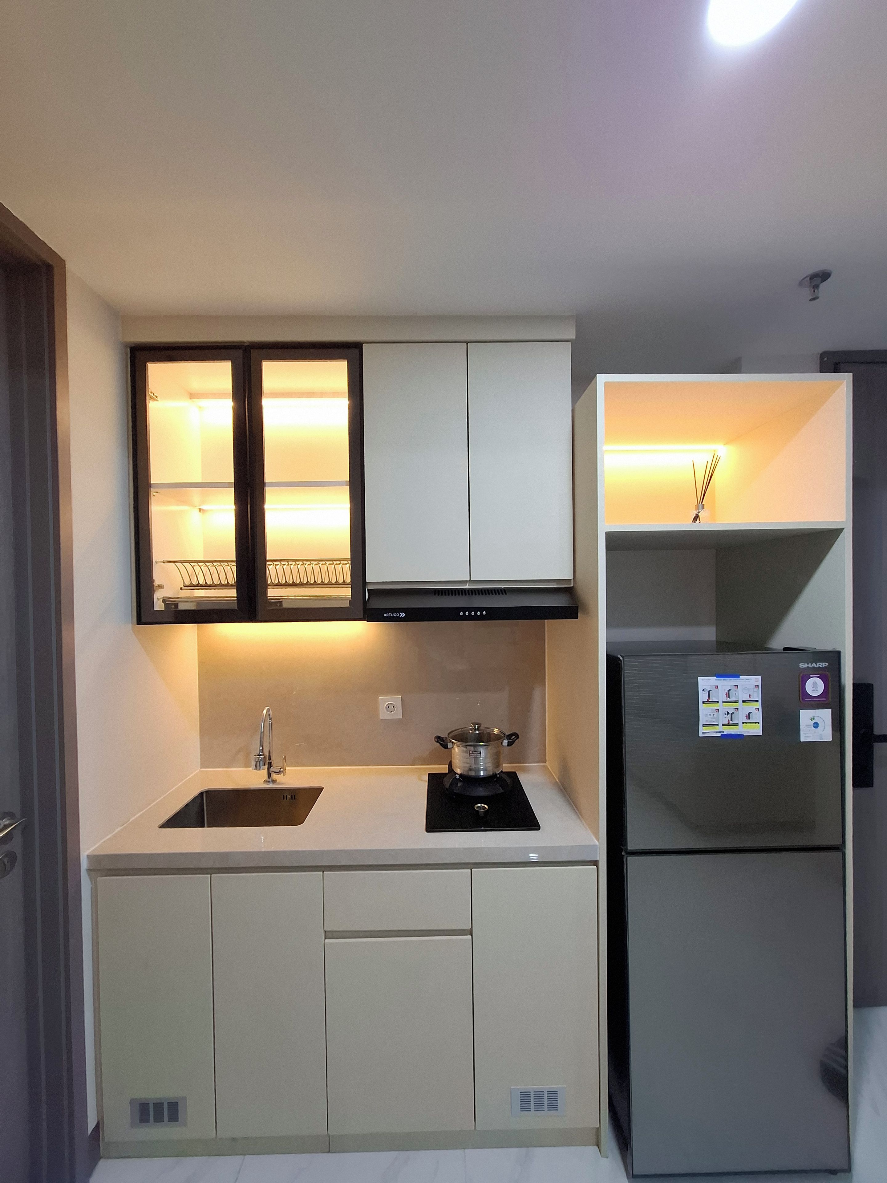 Uma cozinha compacta com pia, fogão e um armário de portas duplas acima.