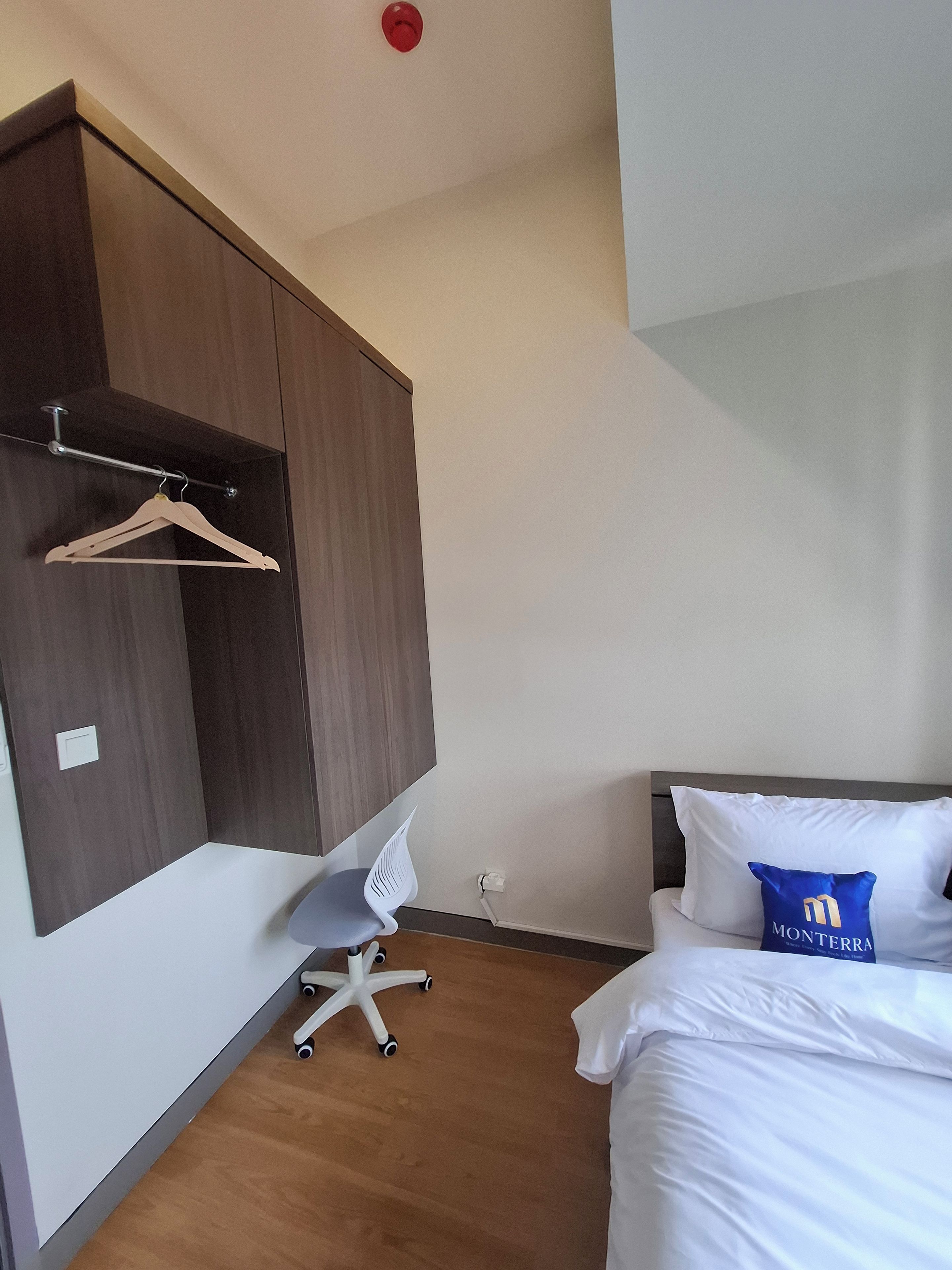 Um quarto com cama, escrivaninha e armário.