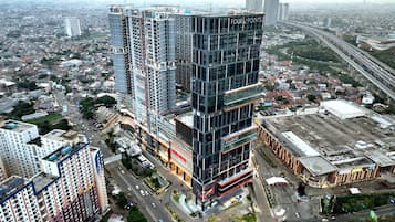 Um edifício de vários andares com fachada de vidro moderna, inserido em um ambiente urbano movimentado com ruas e outros edifícios.