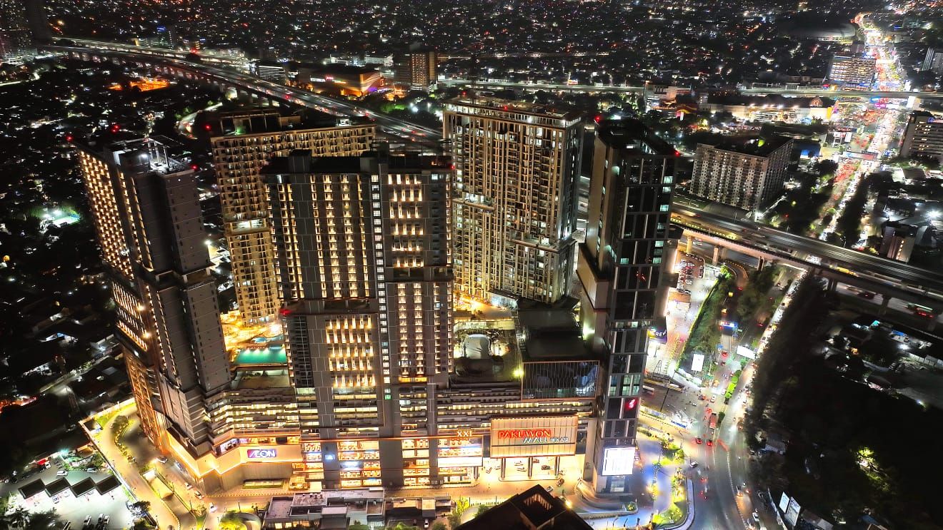 Um edifício alto com vários andares, situado numa área urbana bem iluminada à noite.