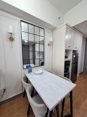 Uma cozinha moderna com armários brancos, bancada de mármore e forno embutido.