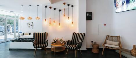 Uma sala de estar moderna com cadeiras listradas, uma mesa redonda de madeira e luminárias pendentes.