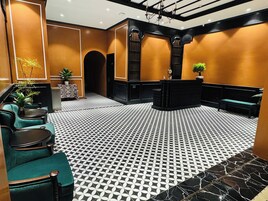 Um hall com piso estampado, área de estar, balcão de recepção e escada.