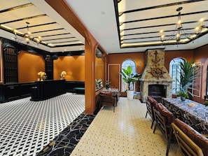 Um saguão de hotel com balcão de atendimento, área de estar, lareira e piso estampado.