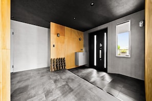 Um interior moderno com piso de azulejos cinza, uma parede de destaque em madeira e uma janela grande.