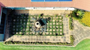 Pátio com um elemento circular central, ladeado por um caminho de pedra, grama e plantas.