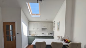 Cozinha moderna com claraboia, porta de madeira e bancada com três banquetes.