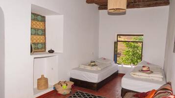 Quarto com duas camas, luminária pendente, janela com vista e cesta de palha.