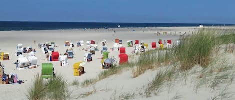 Uma praia com várias cabanas coloridas e uma vista clara do oceano.