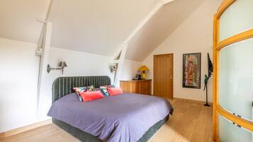Quarto com cama, guarda-roupa de madeira, mesa de cabeceira, luminária e um quadro na parede.
