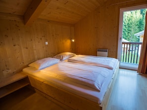 Quarto de cabana de madeira com cama, um banco e uma janela.