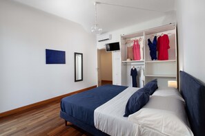 Quarto com cama, guarda-roupa, televisão e ar condicionado fixado na parede.