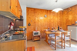 Cozinha com armários de madeira, micro-ondas e sala de jantar com mesa e cadeiras.