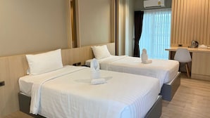 Quarto de hotel com duas camas, uma escrivaninha e uma cadeira.