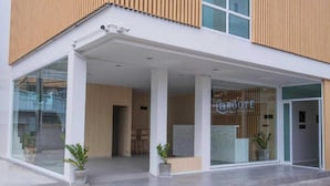 Fachada moderna de um edifício com balcão de recepção, portas de vidro e plantas em vasos.