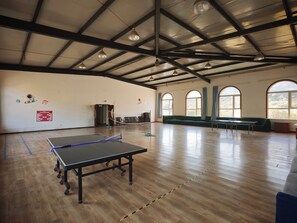 Amplo espaço interno com mesa de pingue-pongue, assentos e grandes janelas.